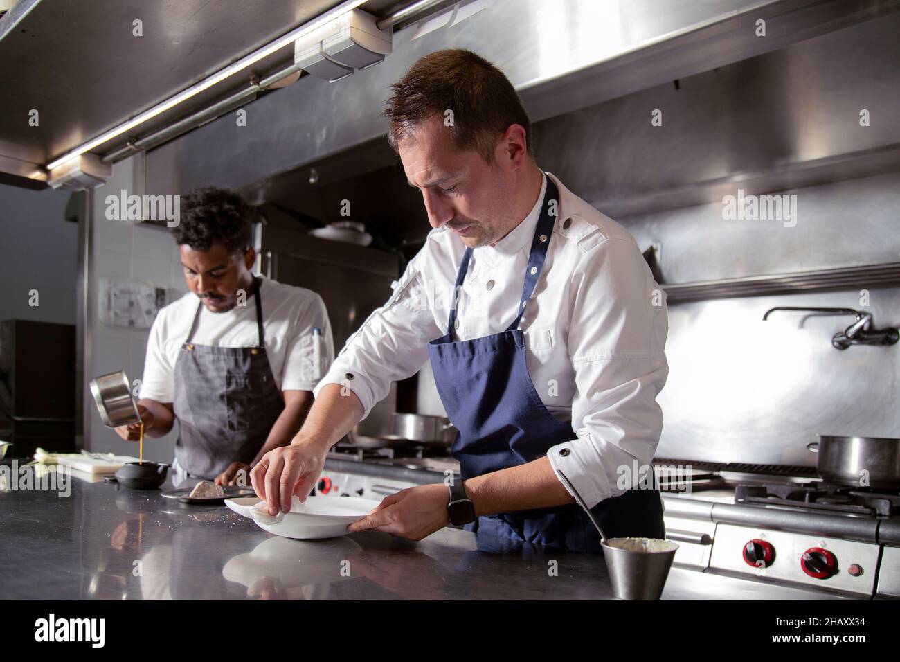 Focused professional chef wiping plate while working with black ...