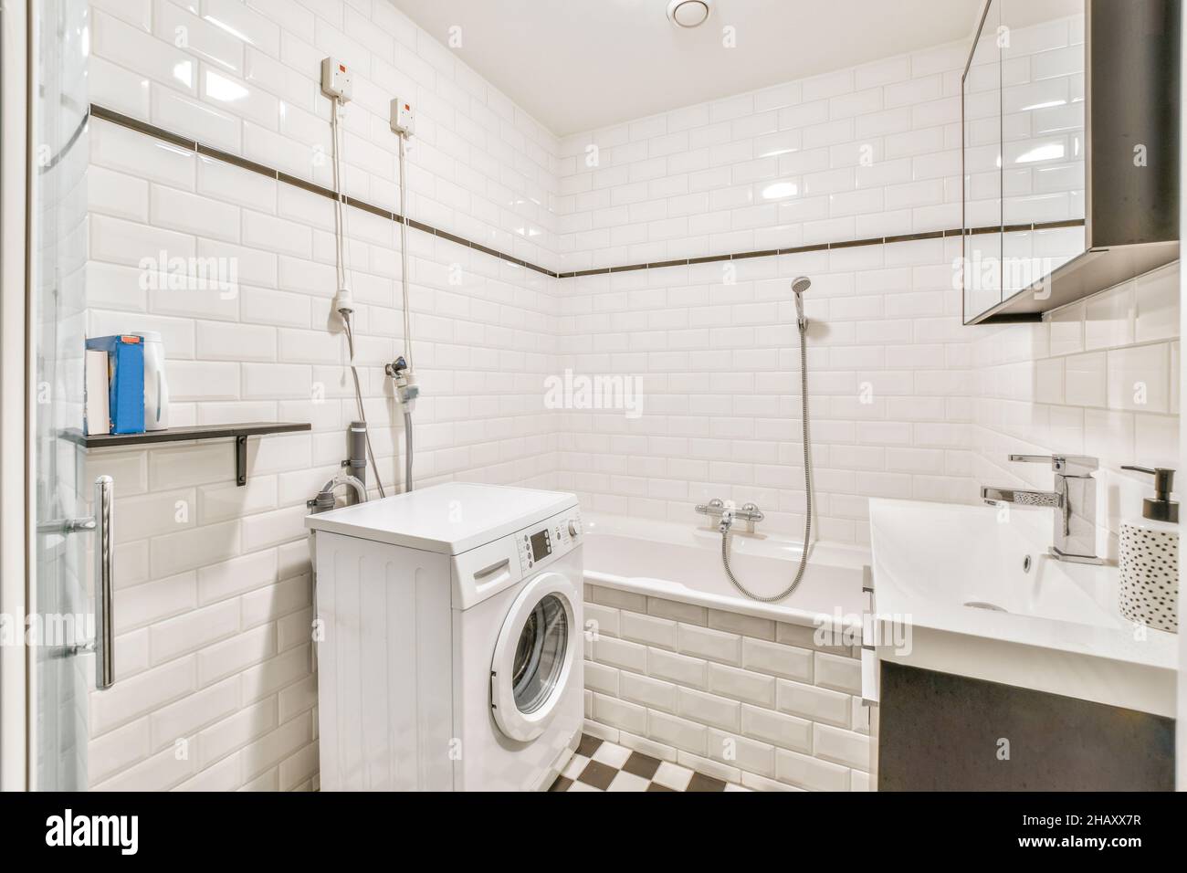 Interior of modern white tiled bathroom with washing machine bathtub ...