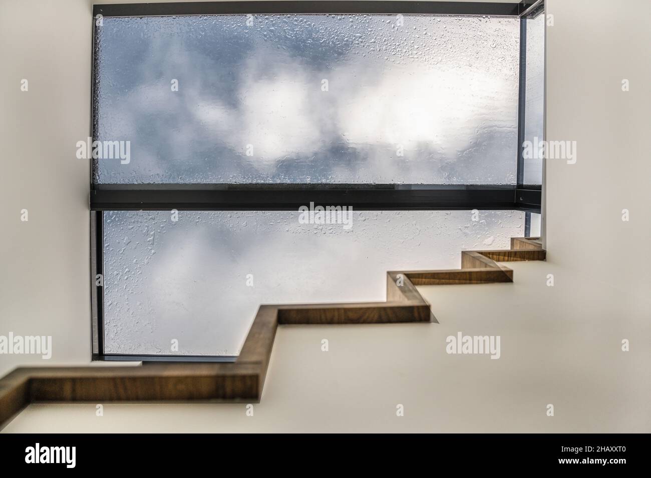 From below glass window on roof and wooden steps of stairway in house ...