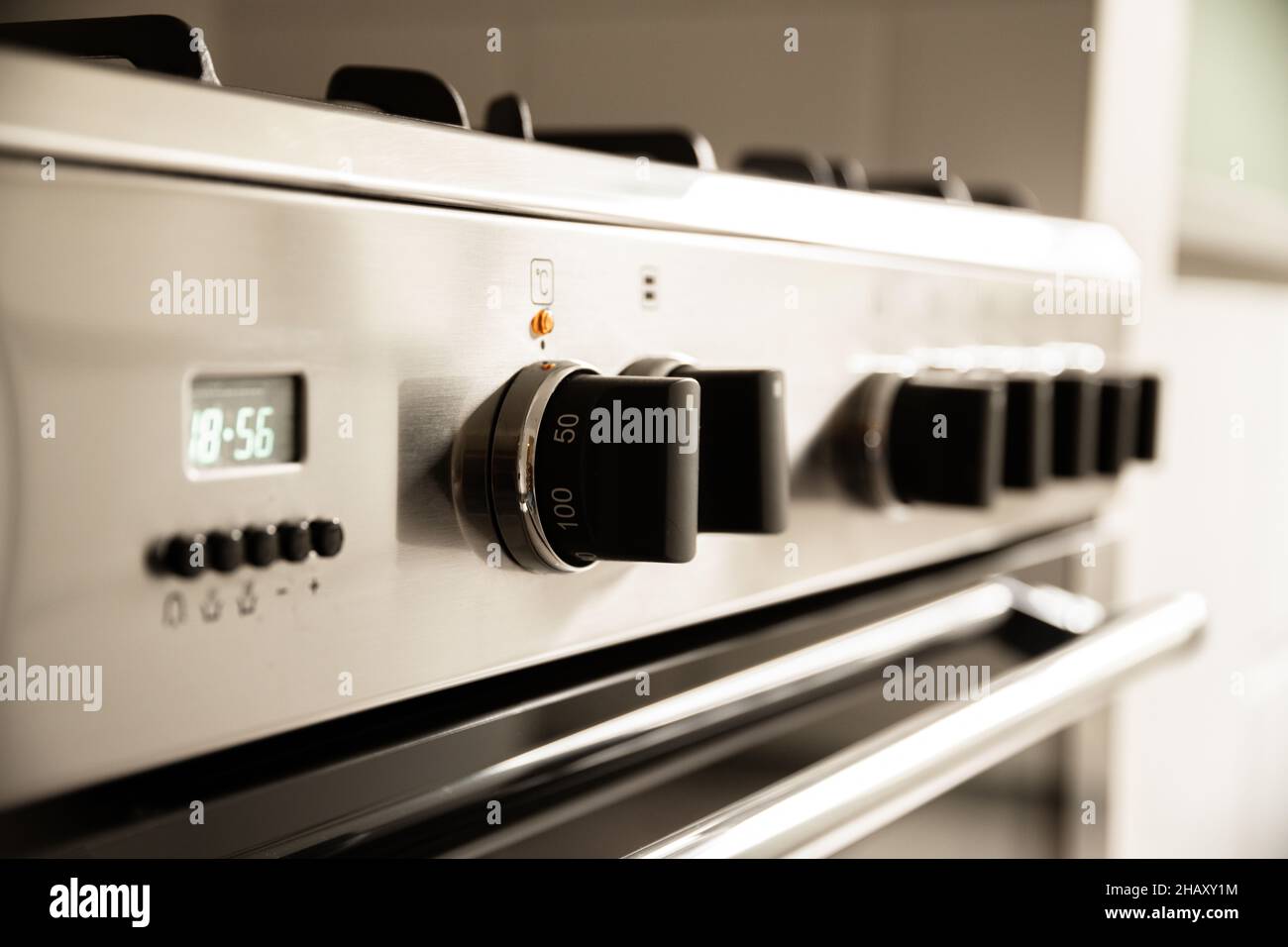 Modern metal kitchen stove with black controllers and glowing display ...