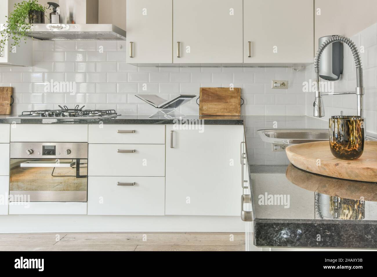 Counter with sink and stove under extract hood placed in light kitchen ...