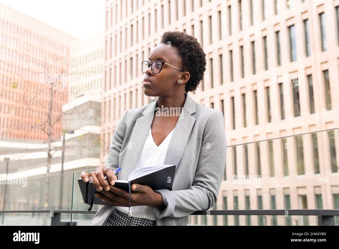 Focused African American female expert taking notes in notebook while ...