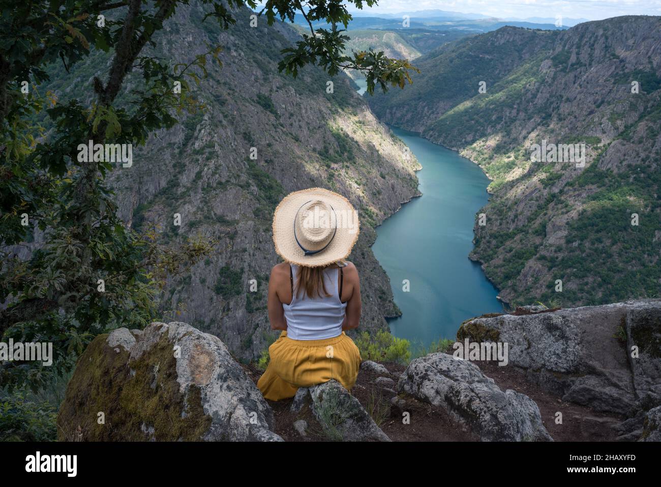 Back view of anonymous traveler Woman sitting on edge of rocky mountain ...