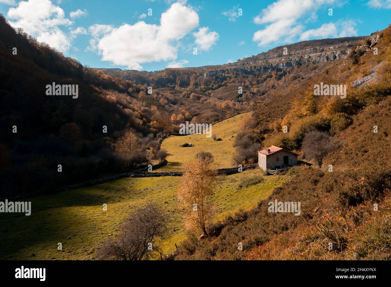 Drone view of small house located in mountainous grassy valley of ...