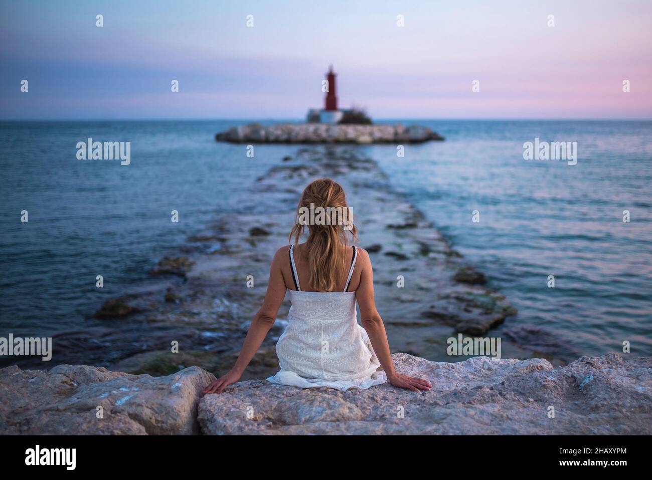 Back view of unrecognizable female traveler in sundress sitting on ...