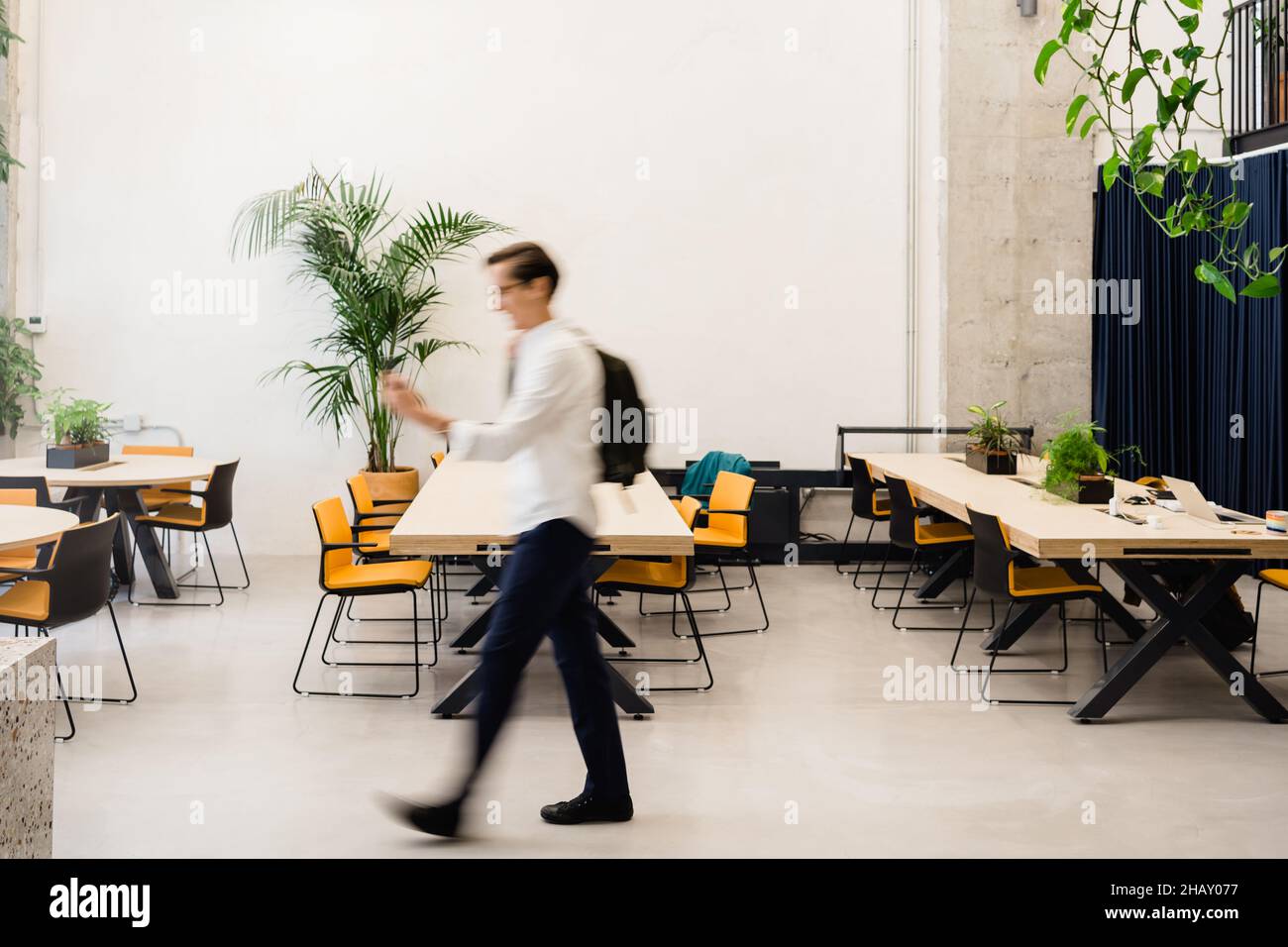 Full body side view of blurred male worker with backpack strolling in ...
