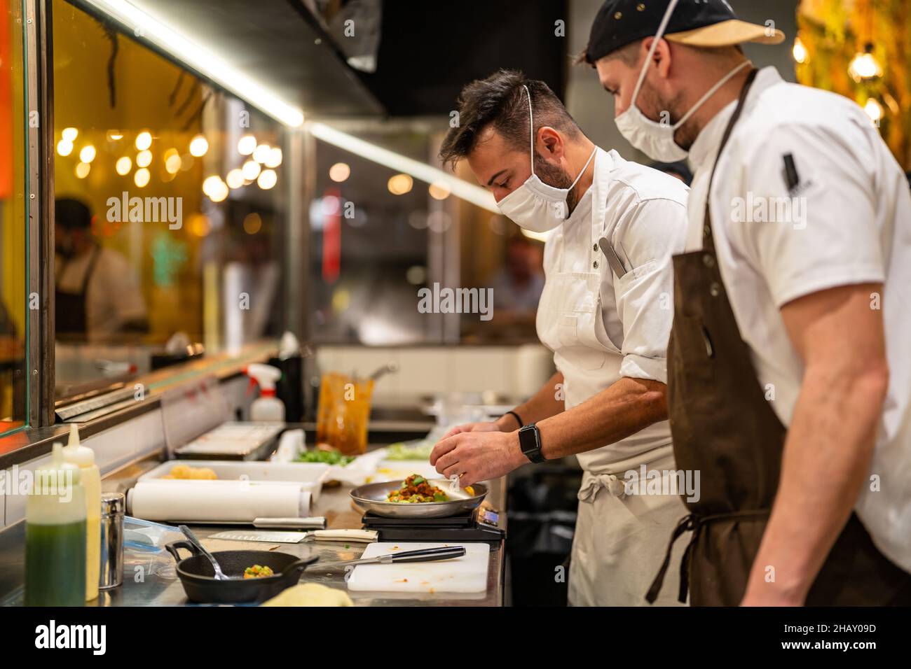 Side view of professional chef in mask serving plate with delicious ...
