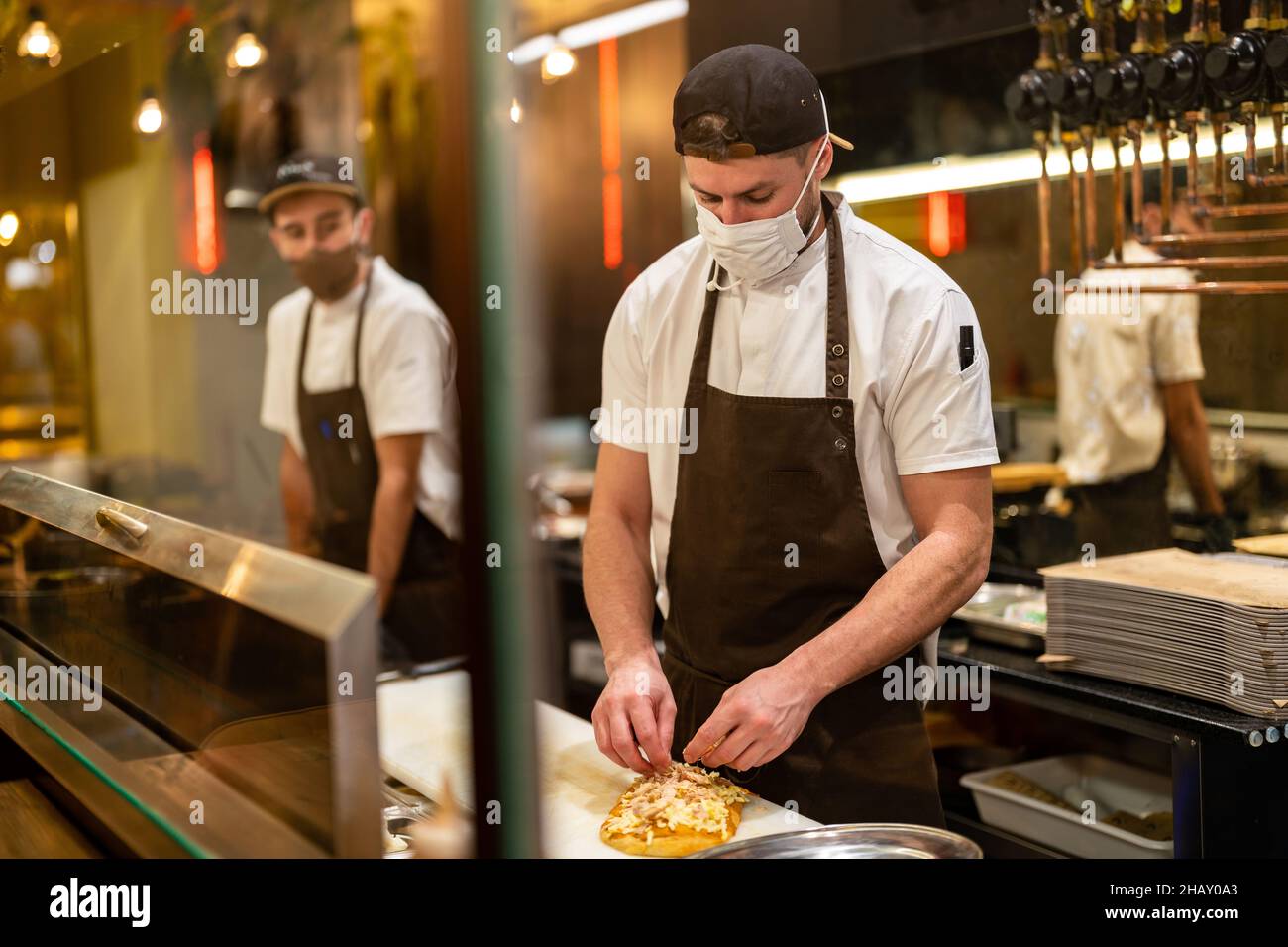 Male cook wearing uniform and mask for coronavirus prevention adding ...