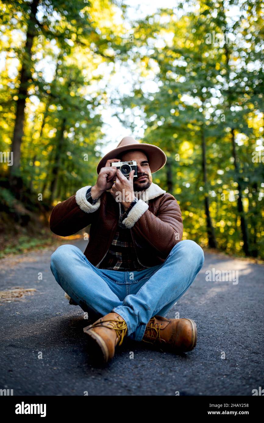 Male photographer in stylish wear taking picture with vintage camera of ...