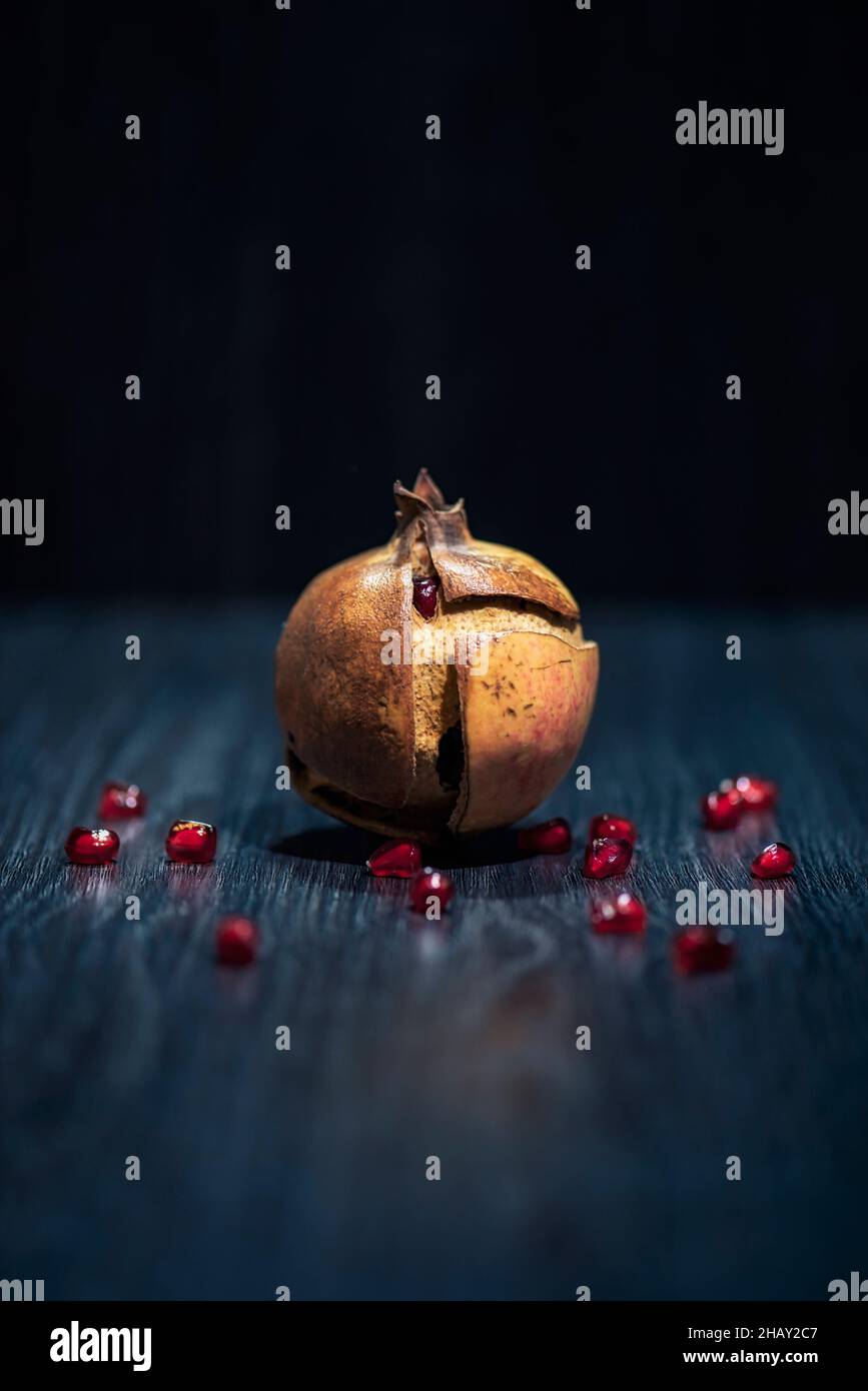 Front view of of overripe half peeled pomegranate placed on dark ...