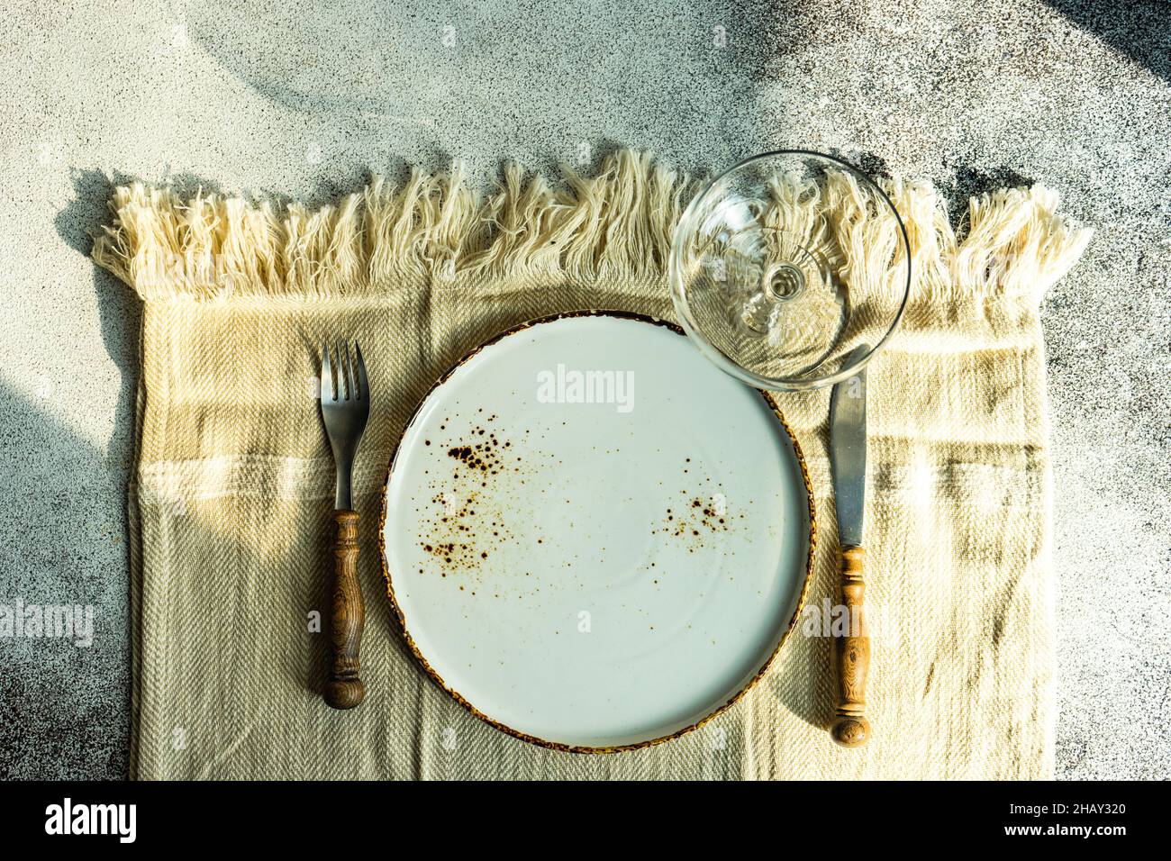 Overhead view of a rustic place setting, wine glass and tablecloth ...