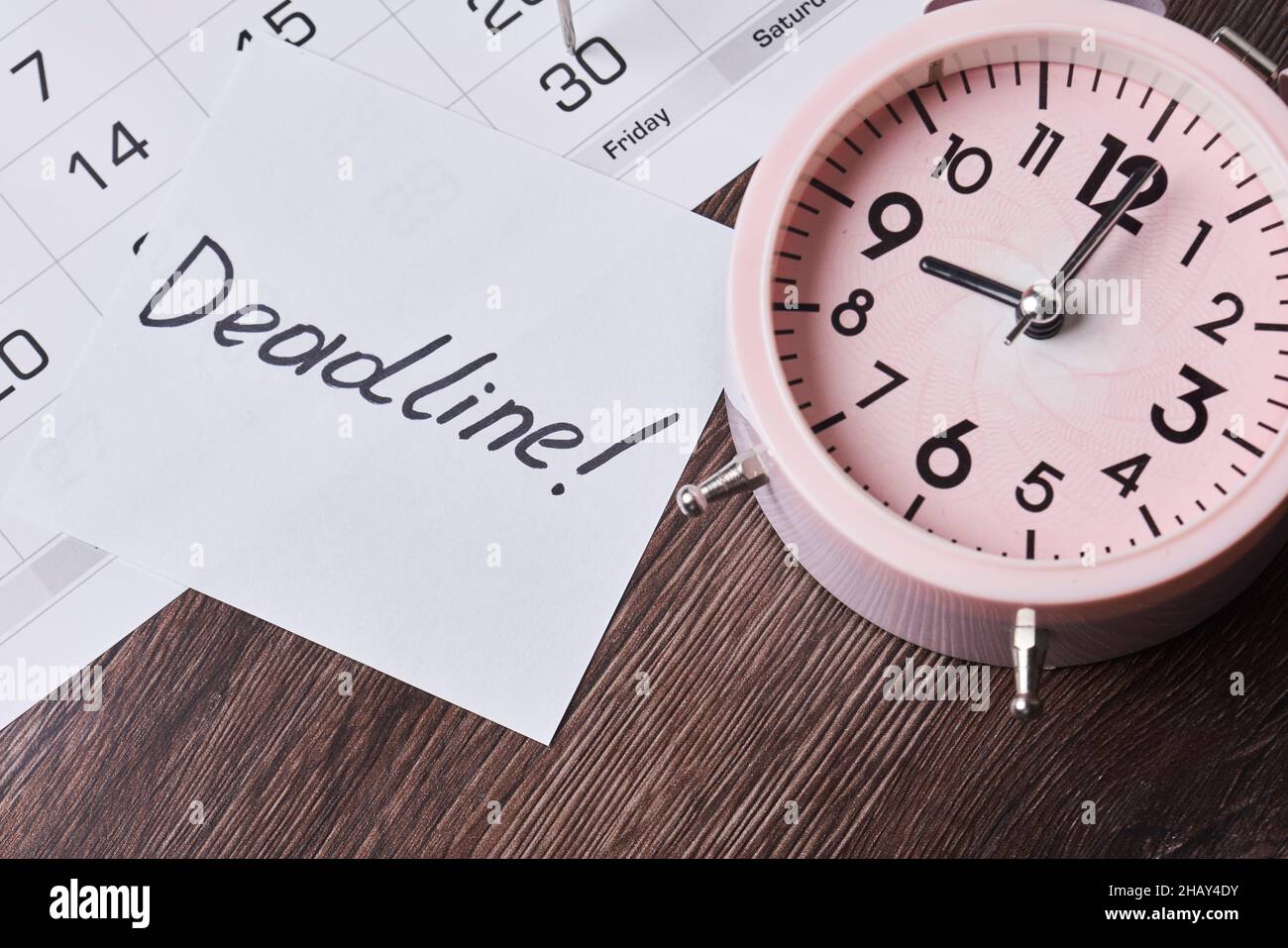 Deadline text on piece of paper, alarm clock and monthly calendar on ...