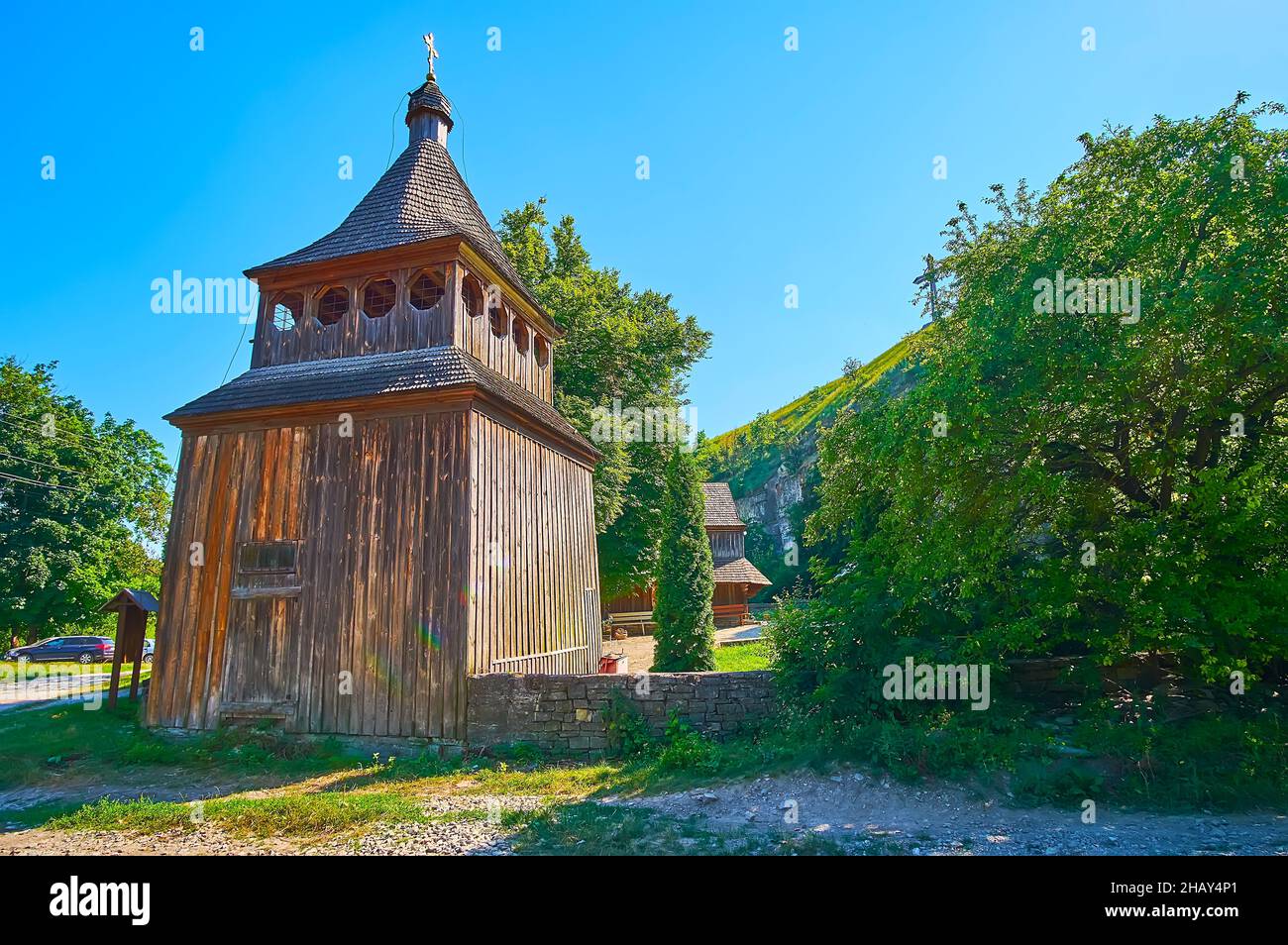 The spread green trees around the old wooden belfry of historic ...