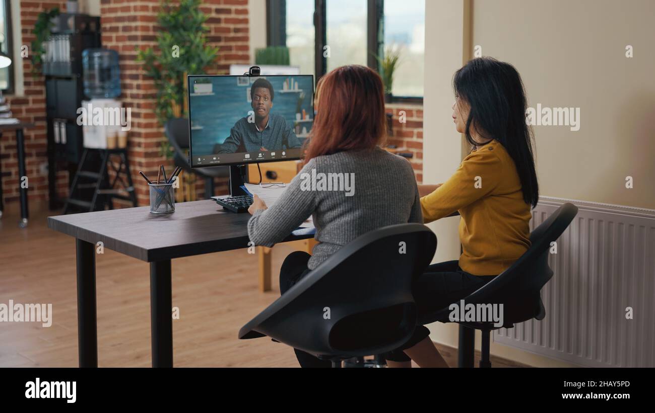 Coworkers using video call on computer to talk to candidate at job ...