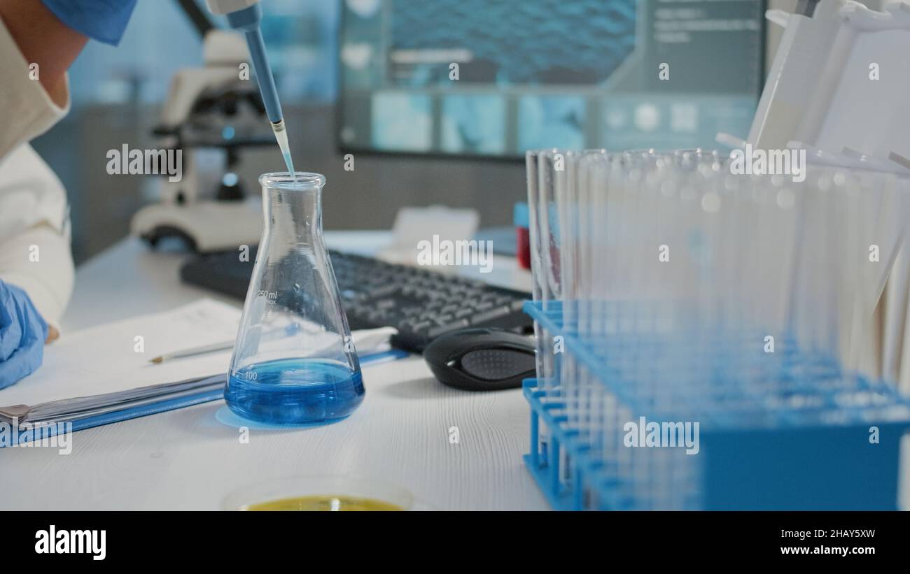 Chemical engineer using micro pipette to put solution in beaker, doing ...