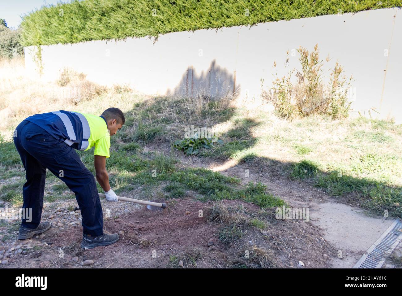 Man in work clothes plowing the land with a hoe Stock Photo - Alamy