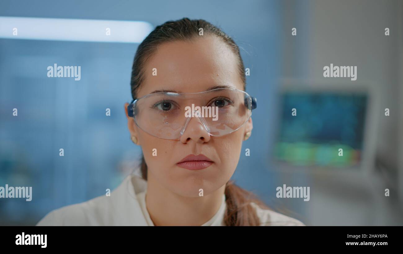 Scientific worker wearing safety goggles in laboratory, working on ...