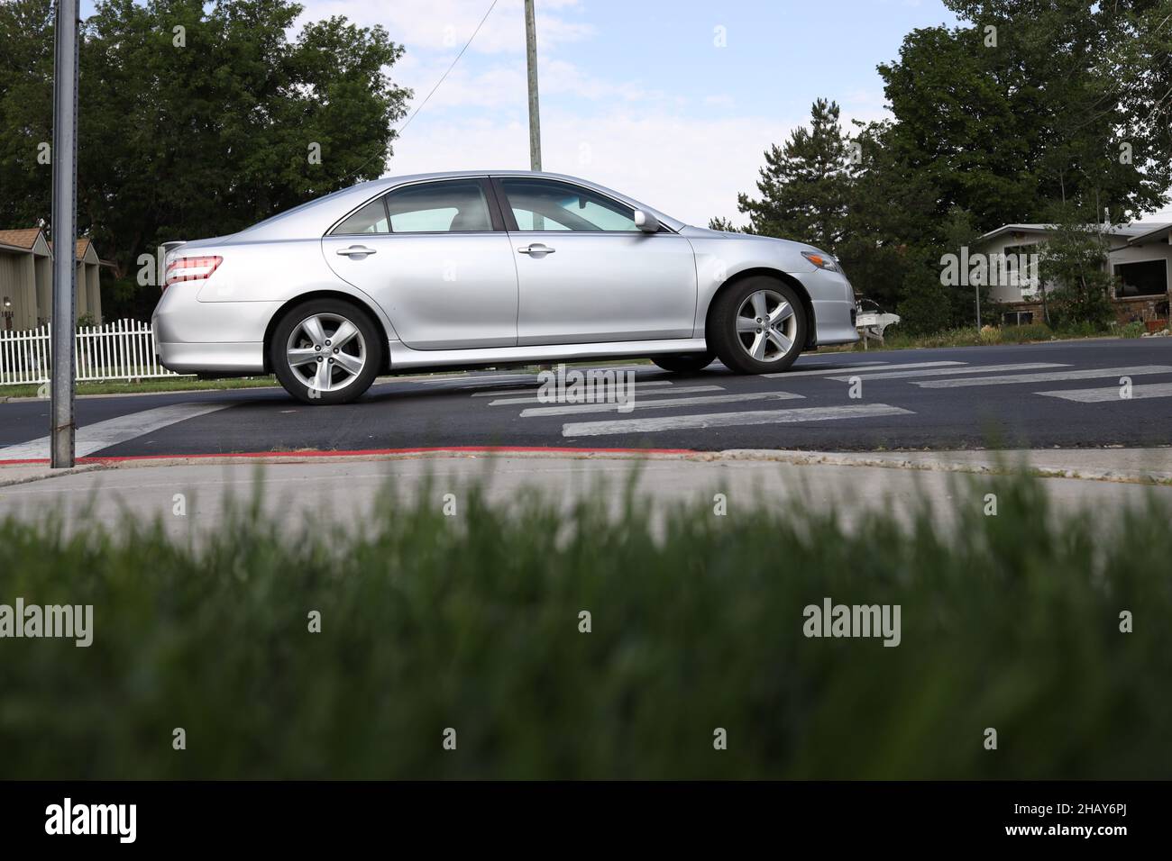 Side view of a silver car driving in the neighborhood Stock Photo - Alamy