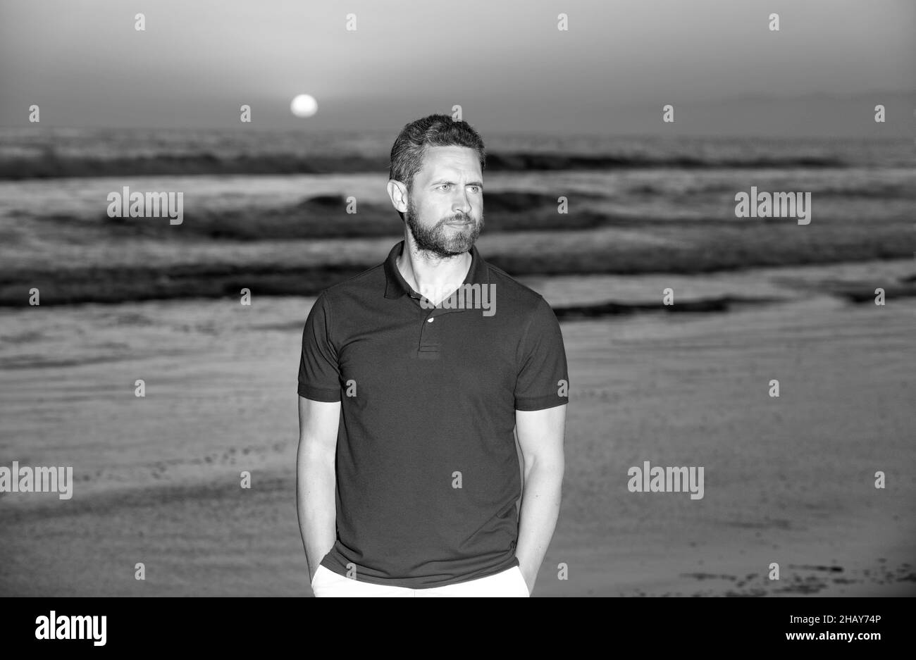 bearded handsome man in summer shirt on beach with sunset over sea ...