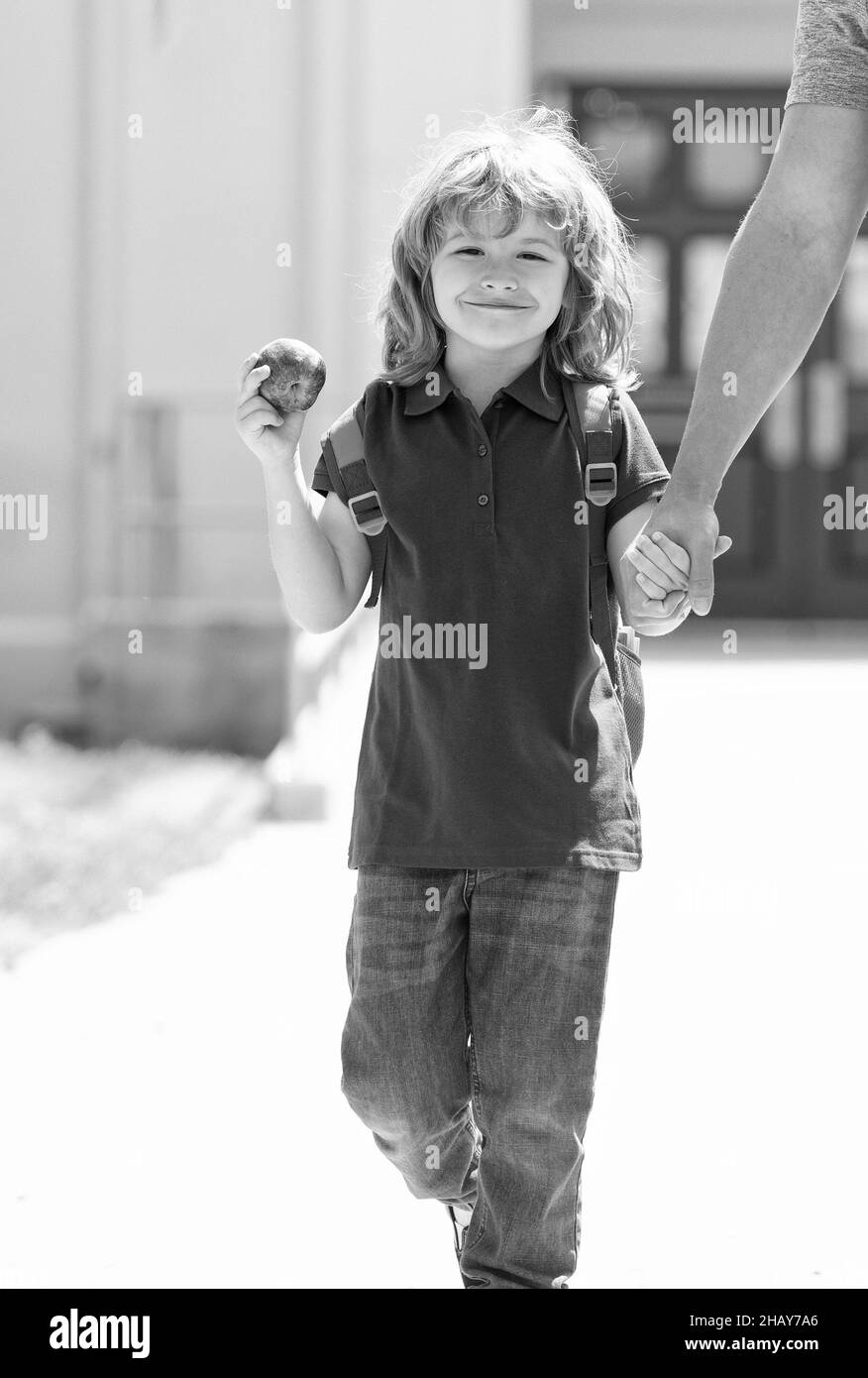 smiling pupil kid hold apple and dads hand coming back from school ...