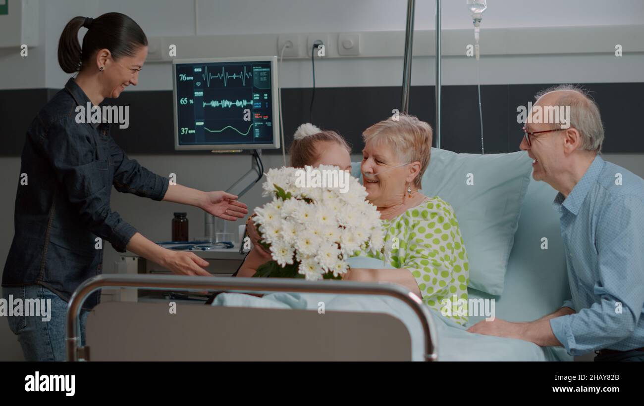 Little girl and woman bringing flowers to visit ill patient in hospital ...