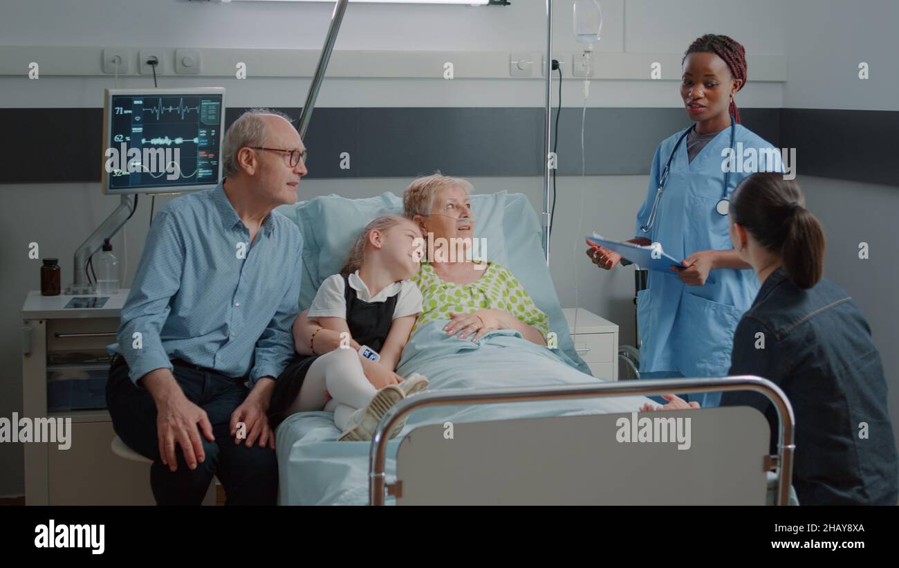 Medical assistant explaining diagnosis to ill woman and family in ...