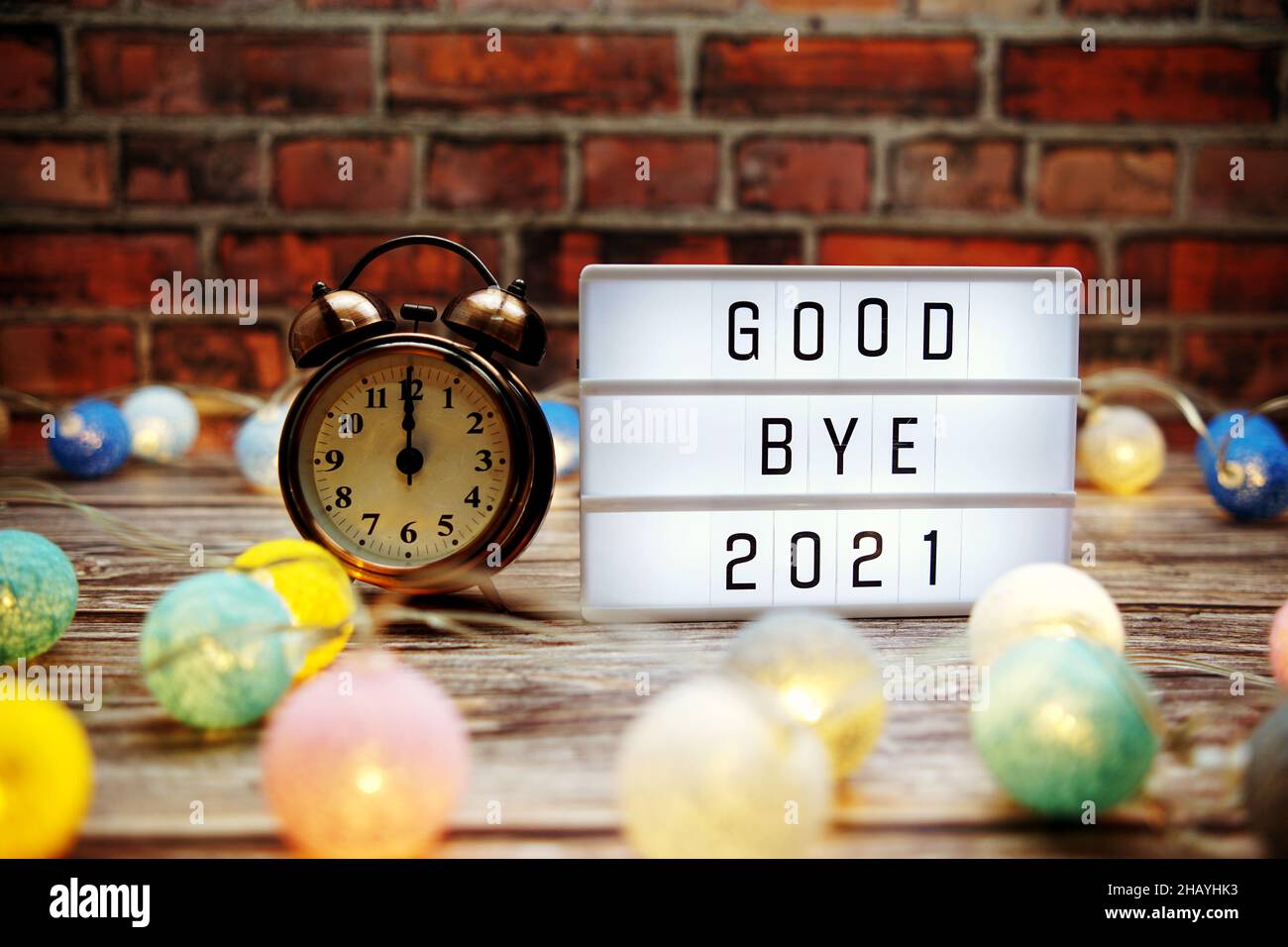 Goodbye 2021 text in light box with alarm clock and LED cotton balls ...
