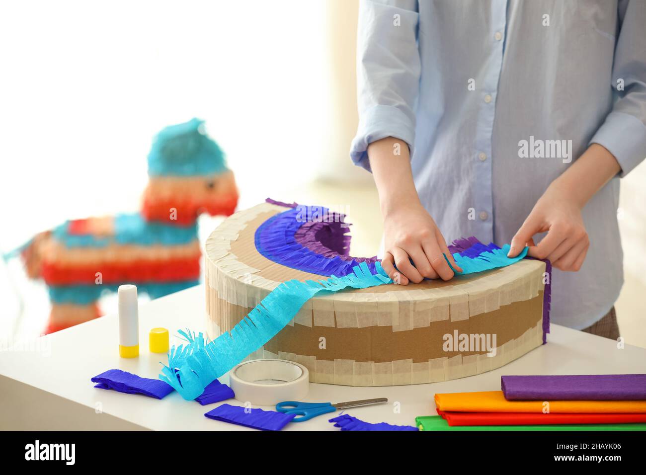 Woman making Mexican pinata in shape of rainbow at table Stock Photo ...