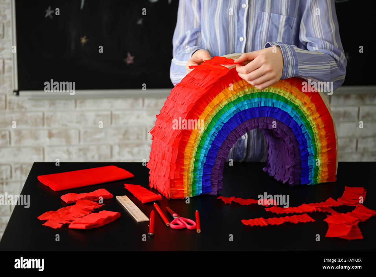 Woman making Mexican pinata in shape of rainbow on table at home Stock ...