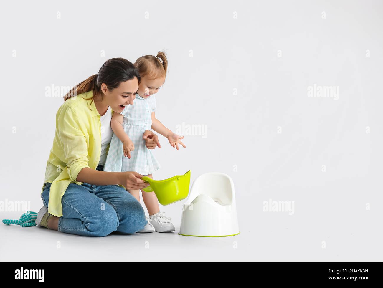 Mother potty training her little daughter on light background Stock ...