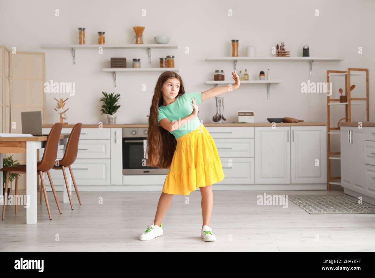 Cute little girl in yellow skirt dancing in kitchen Stock Photo - Alamy