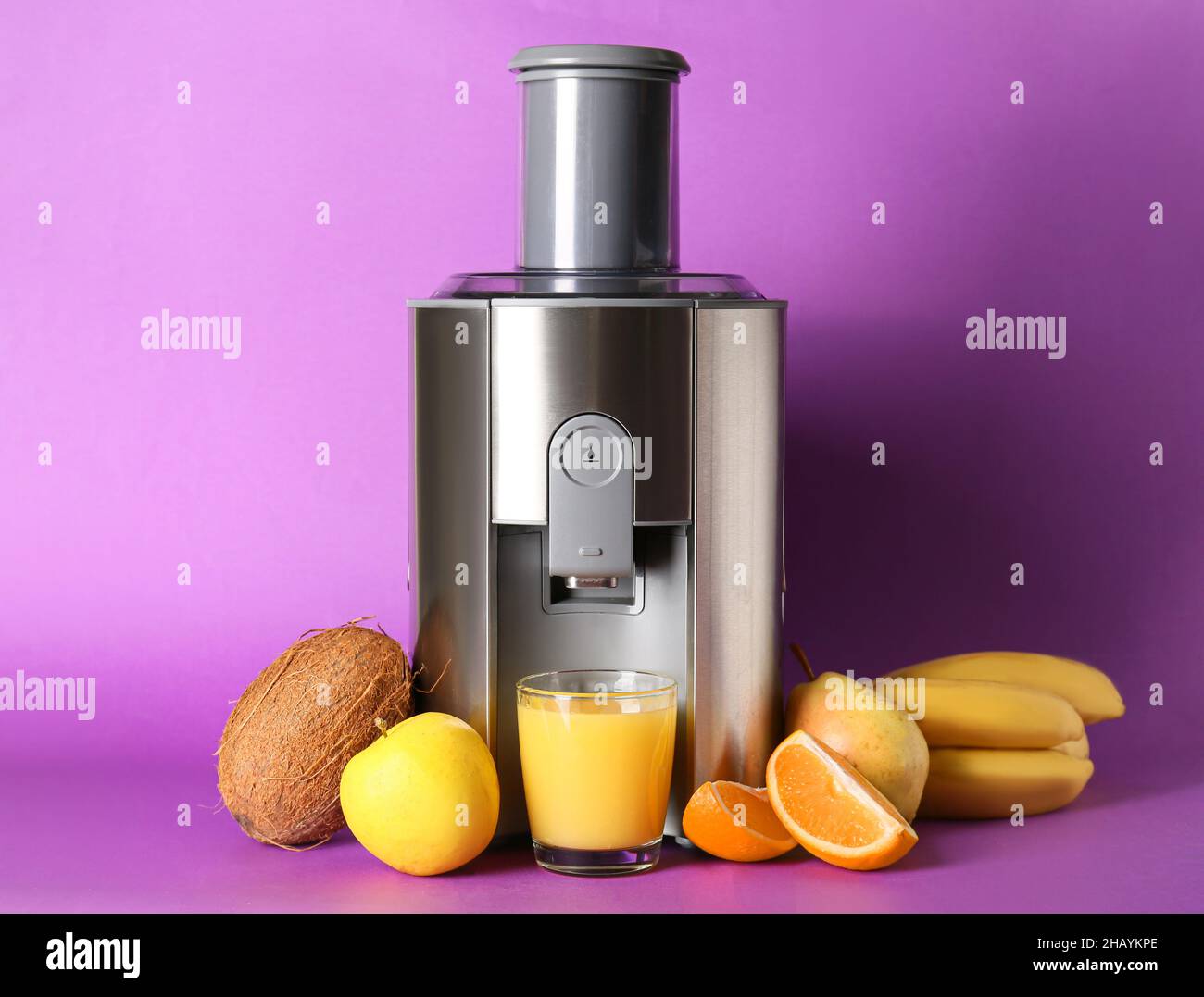 Modern juicer with fresh fruits on purple background Stock Photo - Alamy