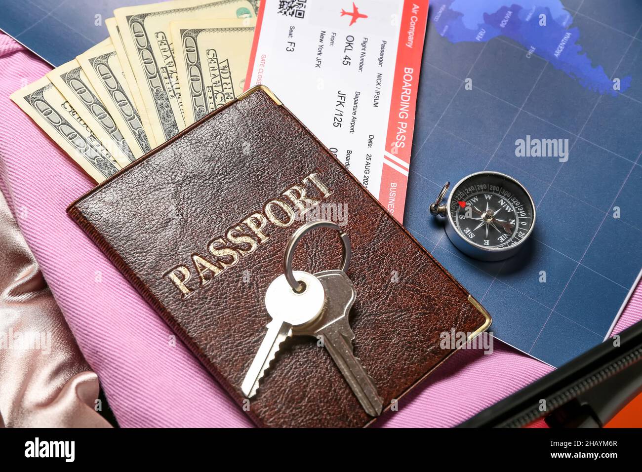 Passport with ticket, money, keys, compass and world map in suitcase ...