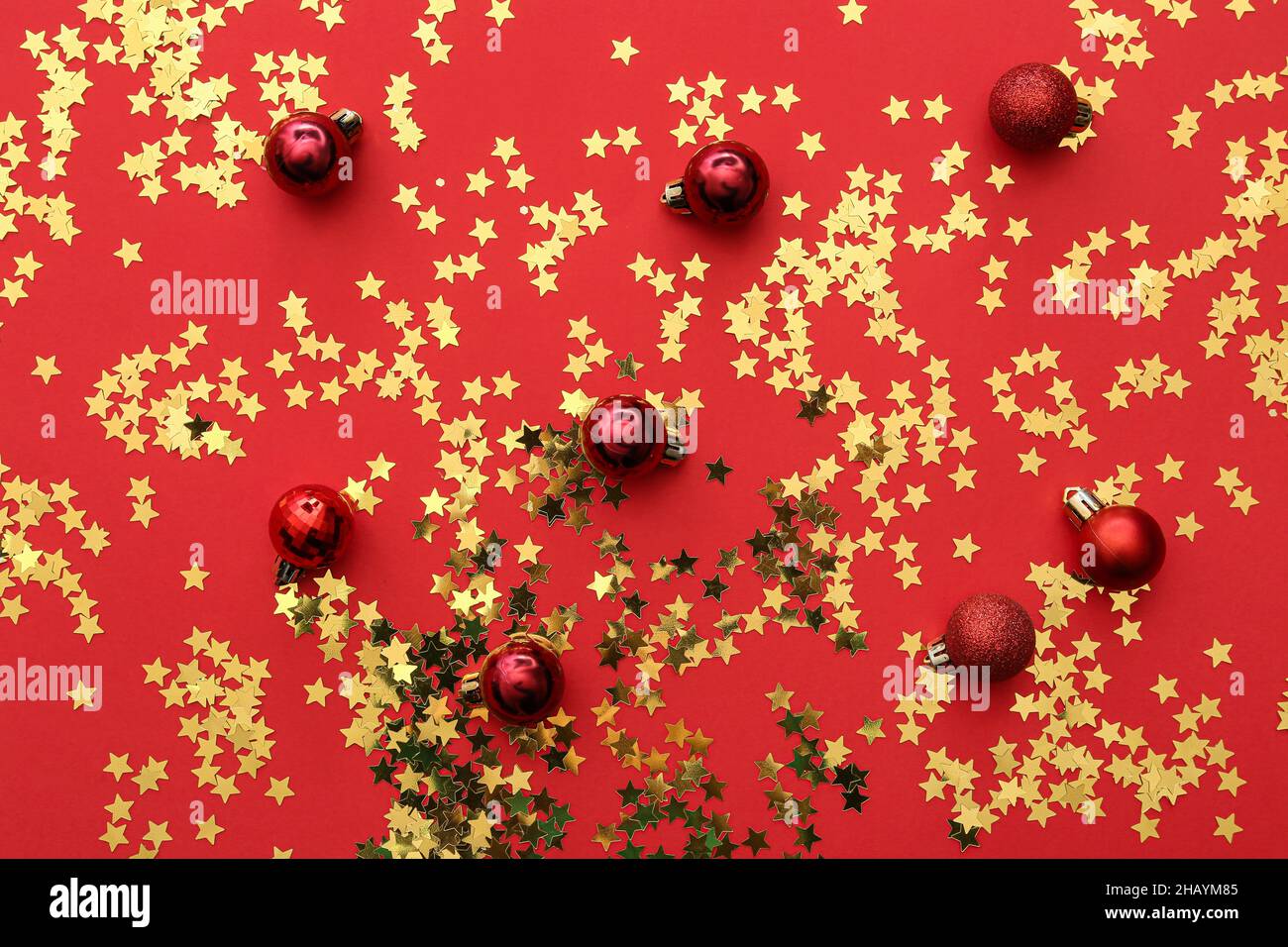 Golden confetti with Christmas balls on red background Stock Photo - Alamy