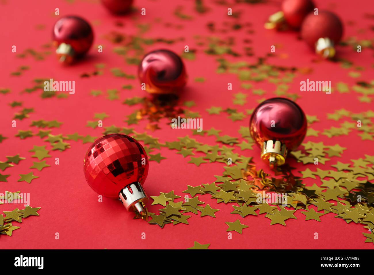 Golden confetti with Christmas balls on red background Stock Photo - Alamy
