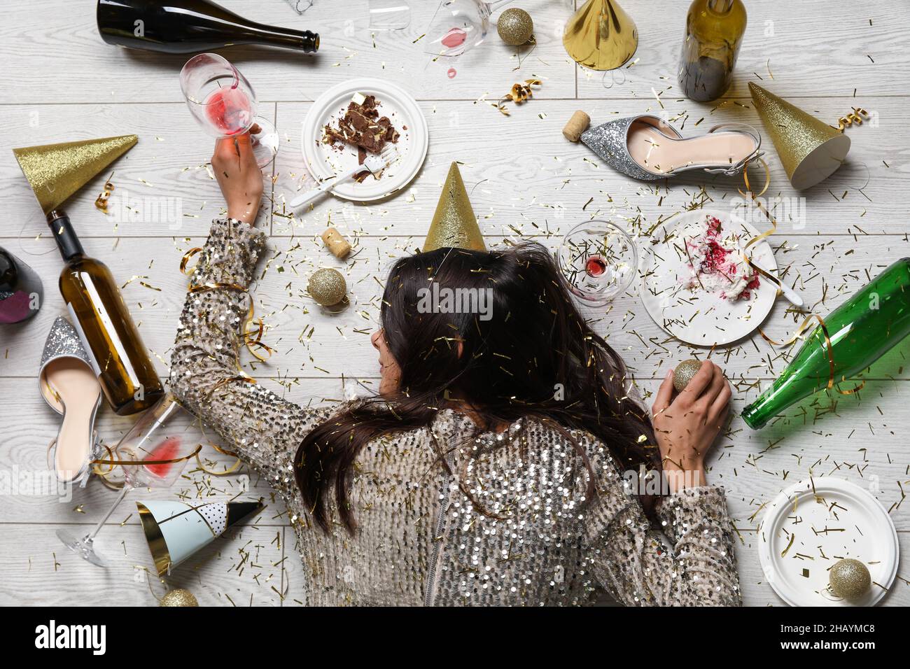 Drunk young woman with wine glass lying on floor after party Stock ...