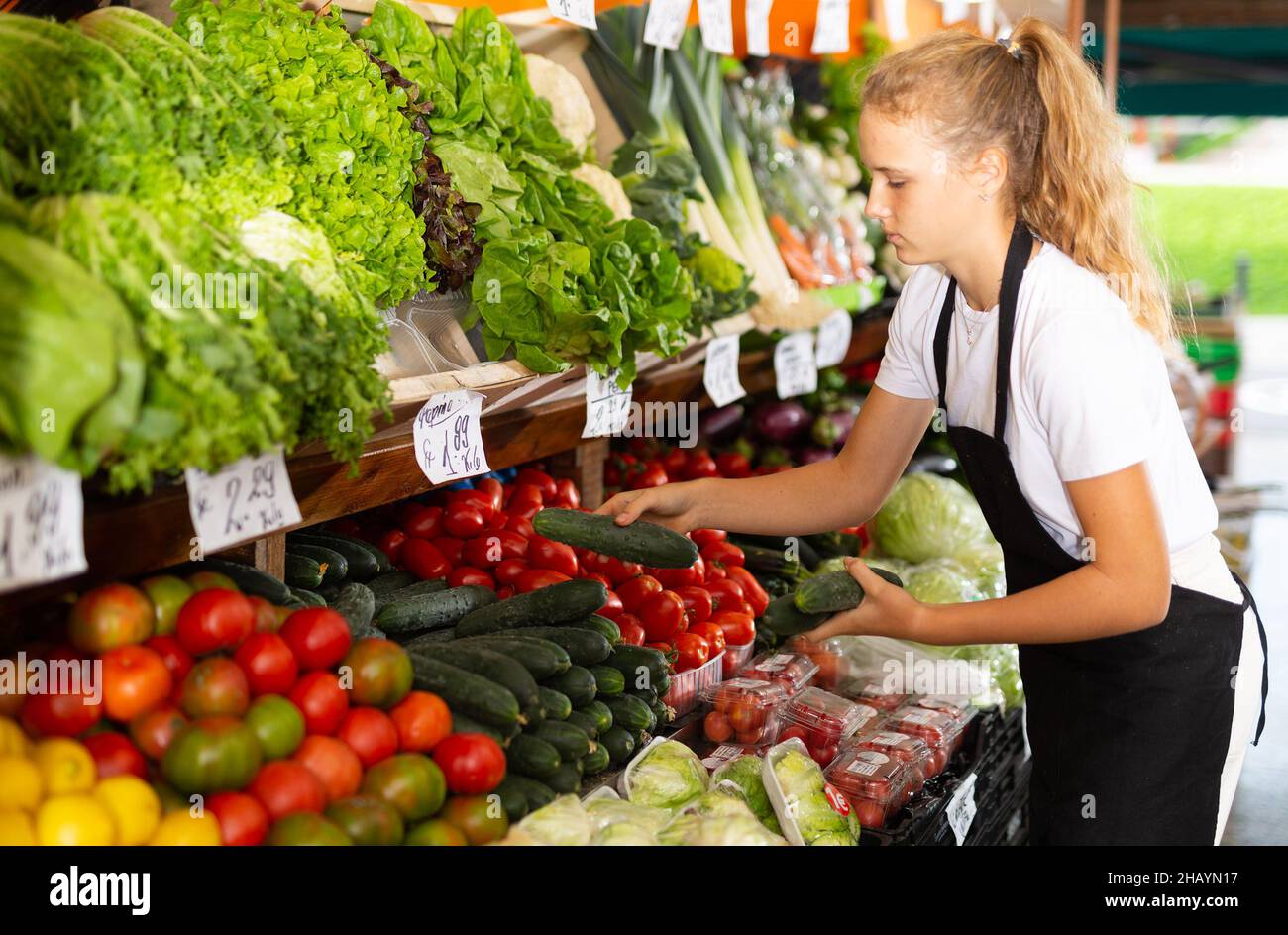 Teenage girl working in grocery, selling cucumber Stock Photo - Alamy