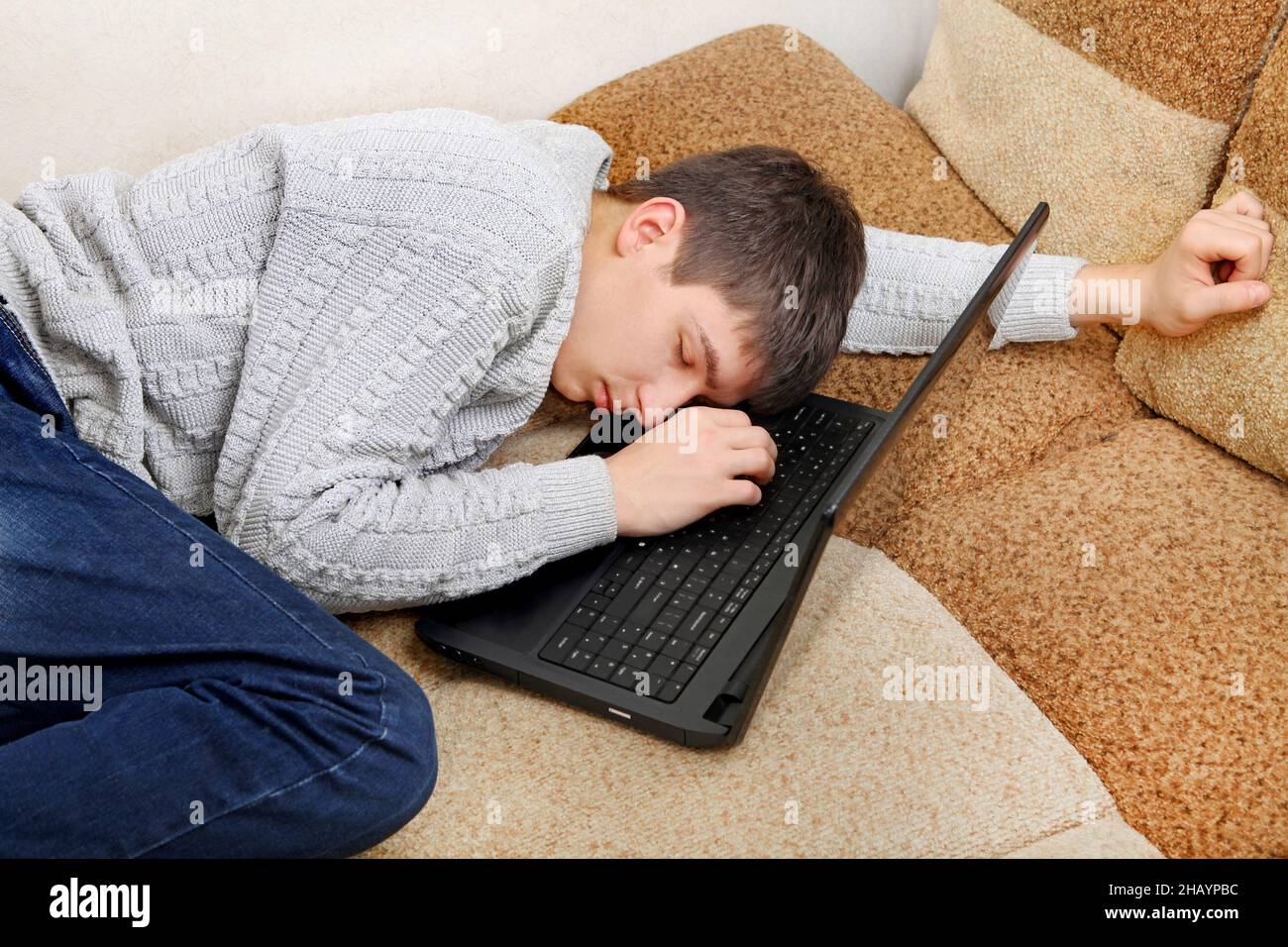 Tired Teenager falling asleep with Laptop on Sofa Stock Photo - Alamy