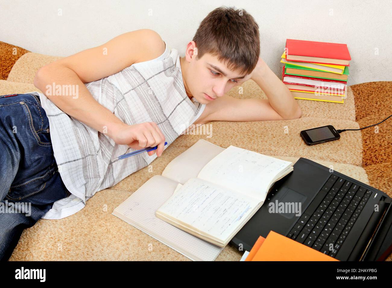 Teenager doing Homework on the Sofa at the Home Stock Photo - Alamy