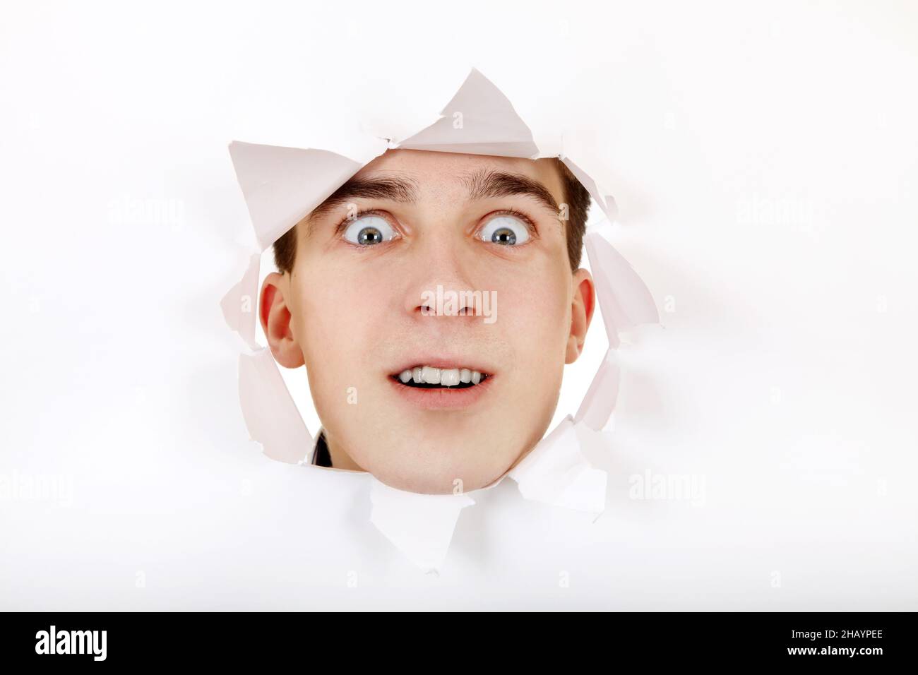 Surprised Teenager peeking through Paper Hole Stock Photo - Alamy