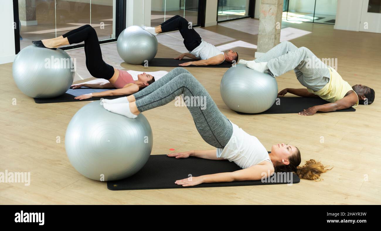 Group of athletic people performing pilates exercises with fitballs ...