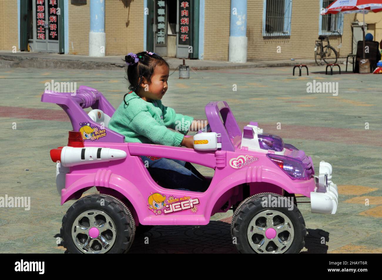 A Chinese girl riding her toy car Stock Photo - Alamy