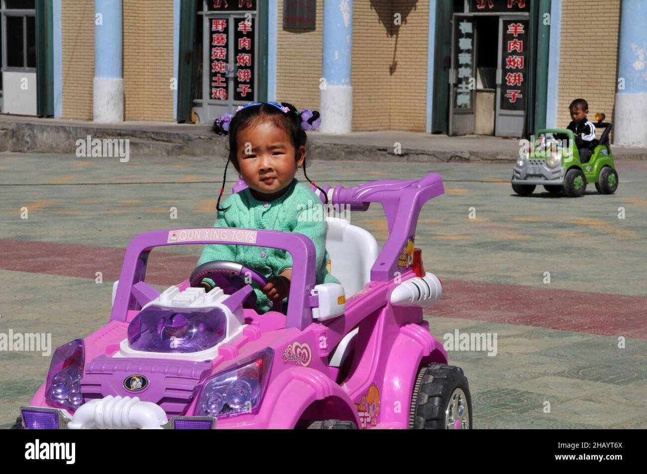 A Chinese girl riding her toy car Stock Photo - Alamy