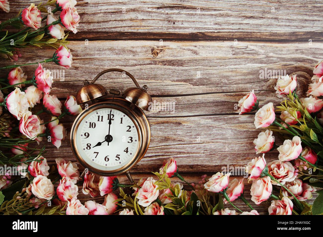 Alarm clock with Pink roses flowers border frame on wooden background ...
