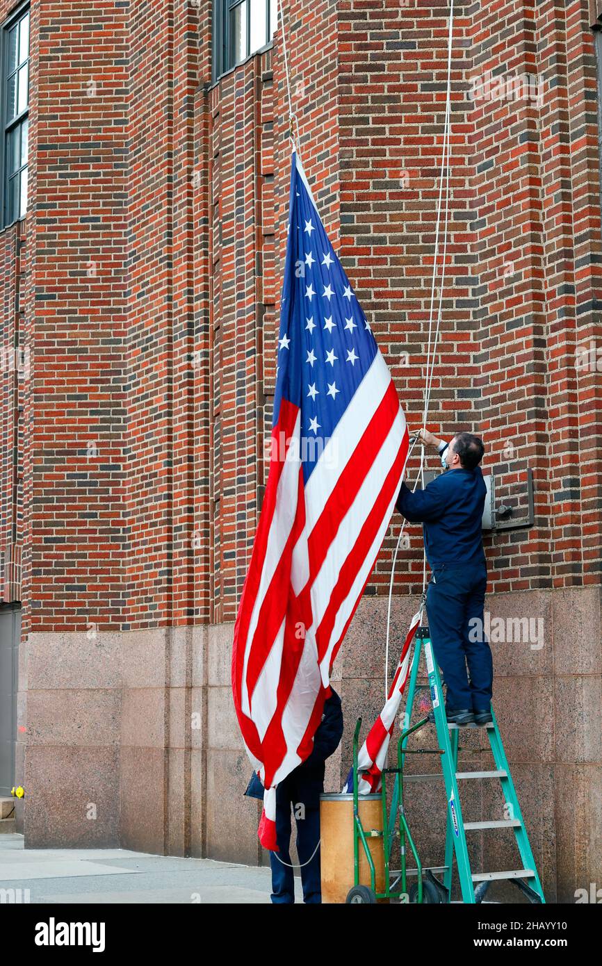 Workers of a New York office building raise the American flag, lower ...