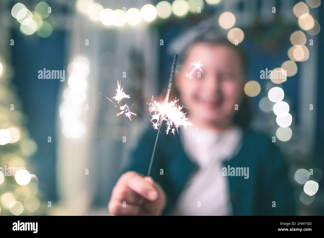 Young girl holding burning sparkler on festive holiday lights ...