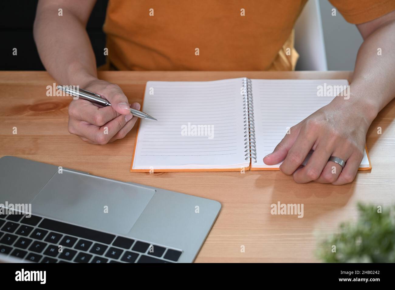Cropped shot man sitting in front of laptop computer and making notes ...