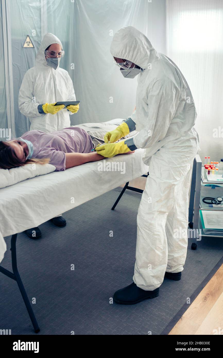 Doctors taking blood sample from patient lying on a gurney Stock Photo ...