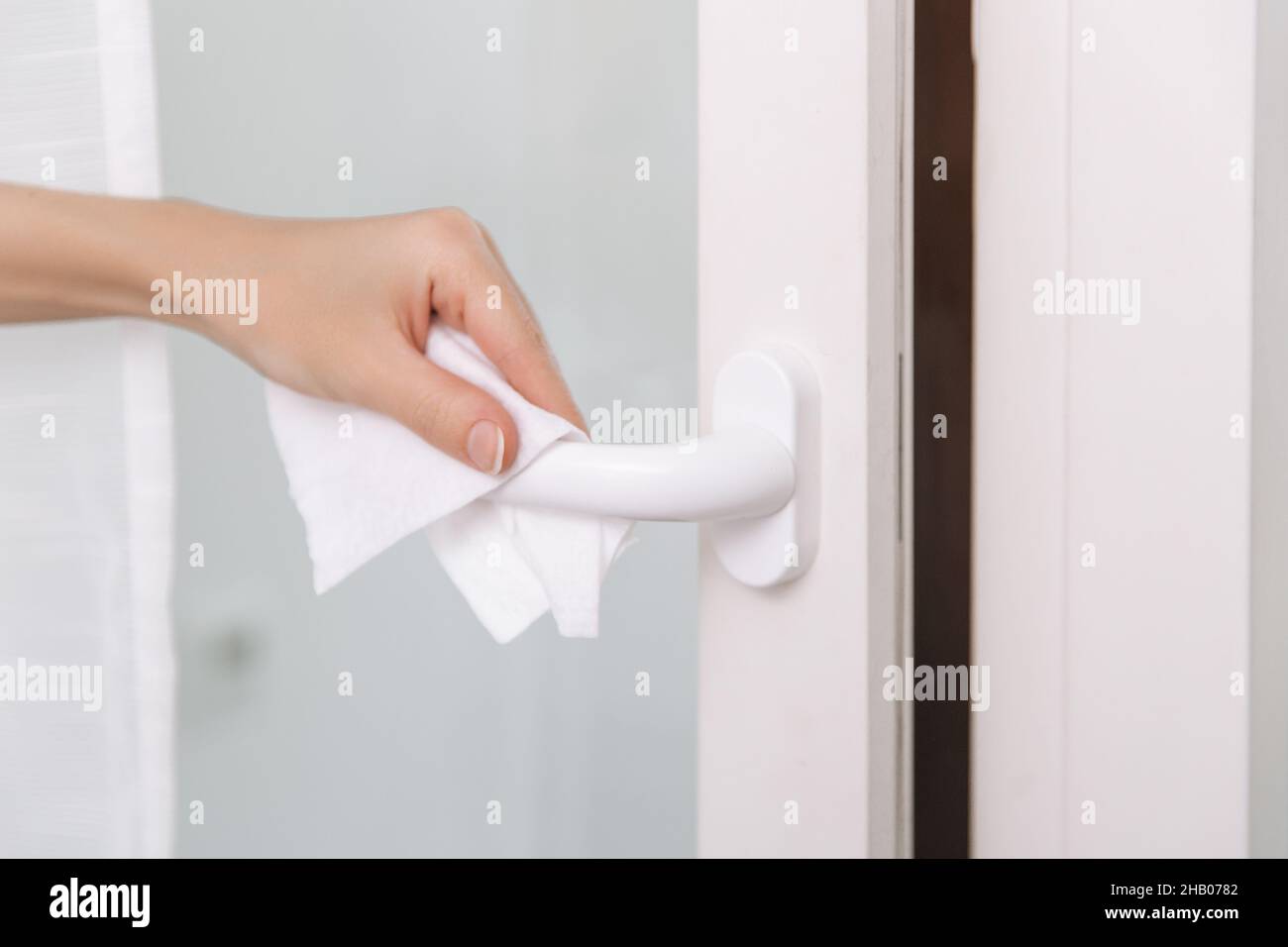 Cleaning door handles with an antiseptic wet wipe and gloves. Woman ...