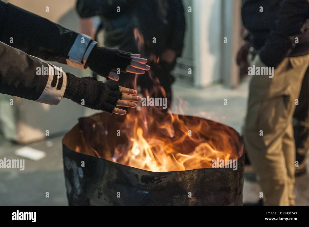Homeless man warming his hands by a fire. Poor men warm outdoors near ...